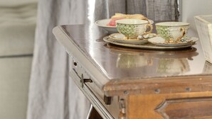 Uma mesa de madeira com um conjunto de chá, incluindo xícaras e pires, e um prato com um doce.