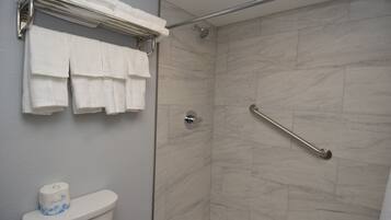 Um chuveiro com barra de apoio, um porta-toalhas com várias toalhas e um vaso sanitário com suporte para papel toalha.