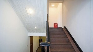 Uma escada com corrimão, teto de madeira e uma placa vermelha na parede.