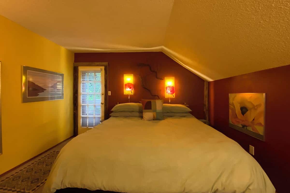 Quarto com uma cama grande, duas luminárias de cabeceira e uma porta com persianas.