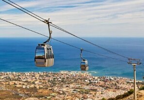Teleférico sobre uma cidade costeira, com vista para o oceano.