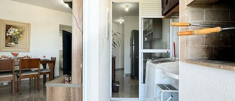 Cozinha moderna com forno embutido, área de refeições com mesa e cadeiras de madeira, e corredor que dá para outro cômodo.