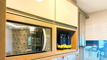 Cozinha com micro-ondas, prateleira com garrafas e painel decorativo.
