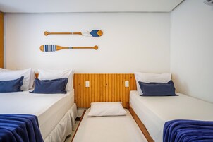 Quarto de hotel com duas camas, uma cabeceira de madeira e dois objetos decorativos na parede.