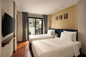 Quarto de hotel com duas camas, televisão, varanda com cortinas e parede estampada.