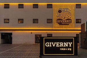 Entrada de hotel com uma placa indicando 'GIVENY Gyeongju' e um letreiro de neon com o mesmo nome.