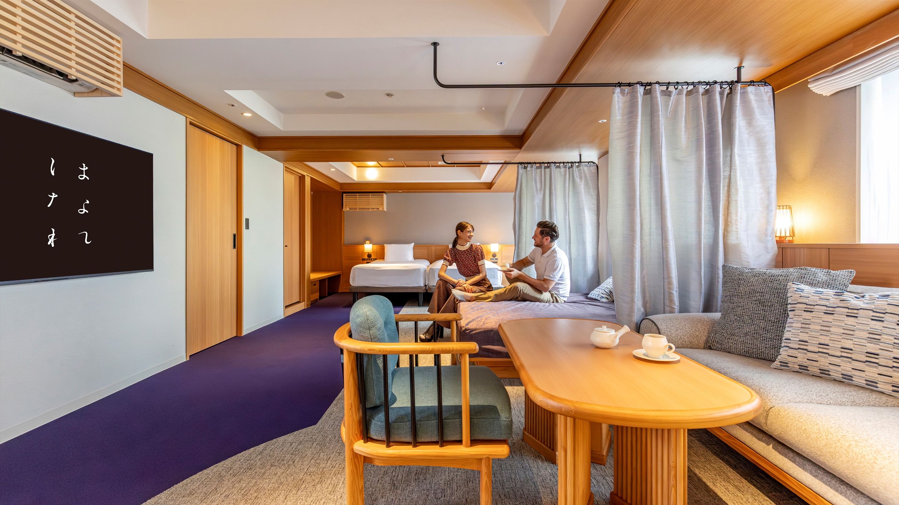 Quarto de hotel com sofá, mesa pequena, cadeira e cama.