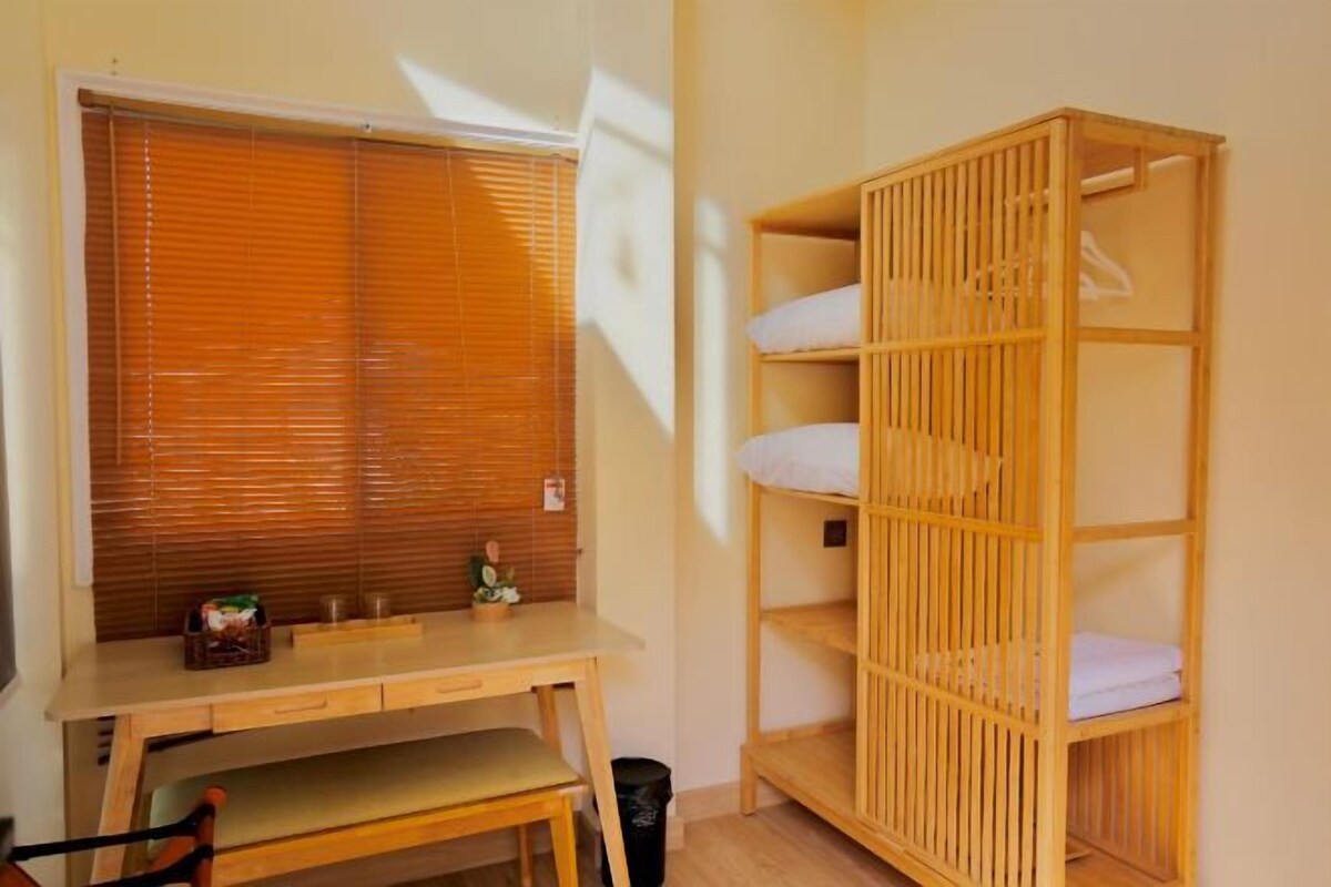 Quarto com escrivaninha de madeira, uma cadeira e uma cama beliche com prateleiras.