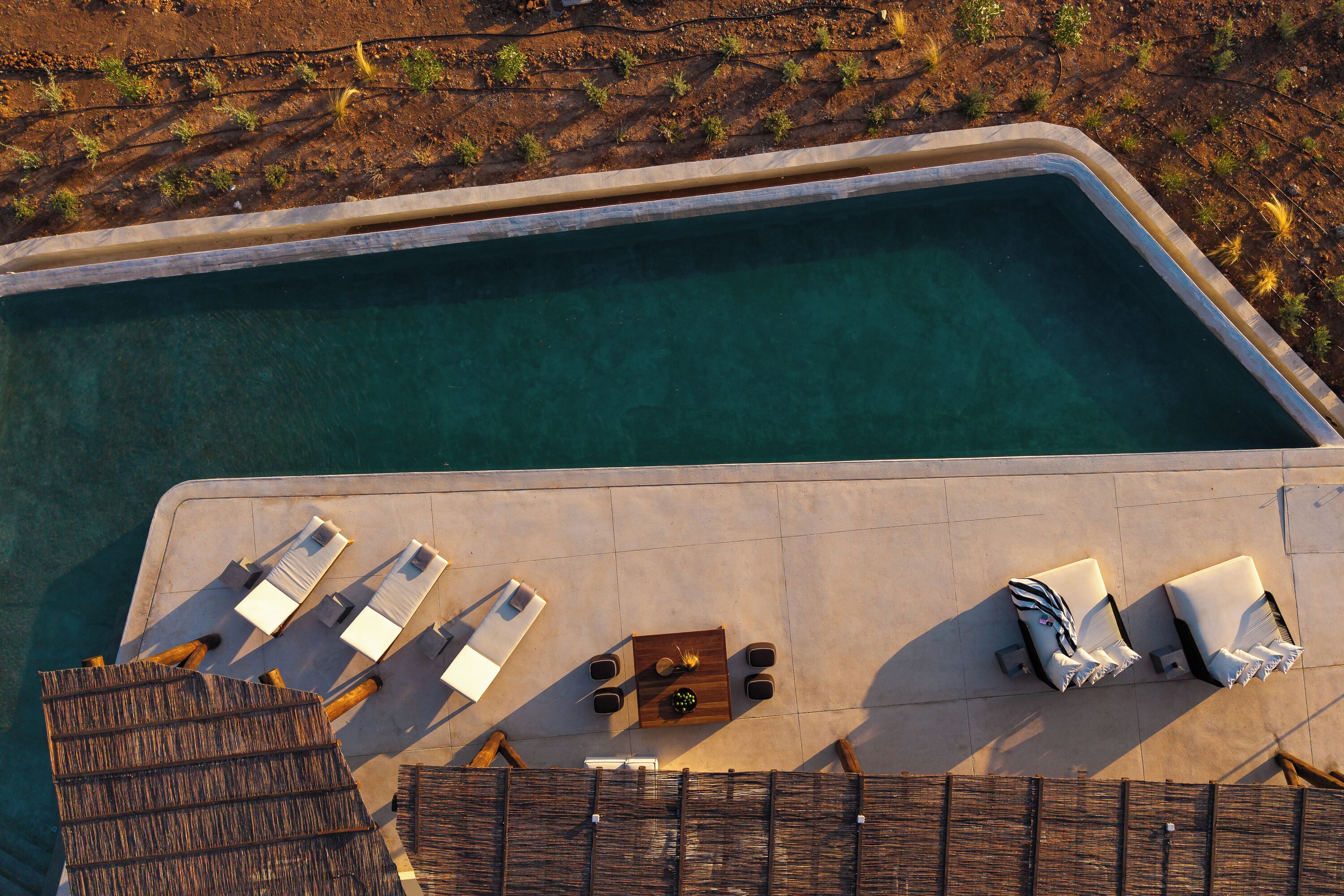Vista aérea de uma piscina com espreguiçadeiras e uma mesa.