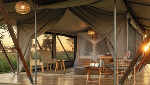 Alojamento em tenda com área de refeições, uma mesa com cadeiras e um candeeiro pendente.