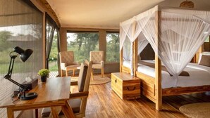 Quarto com escrivaninha de madeira, duas cadeiras, mesa de cabeceira, cama com dossel e janela com vista para árvores.