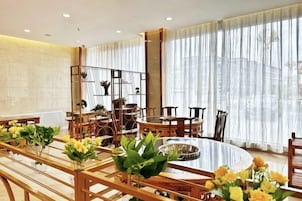 Uma sala de jantar com mesa redonda, cadeiras e plantas em vasos.