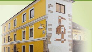 Um edifício amarelo e branco com uma placa que diz 'Eichhof zum goldenen Kreuz'.