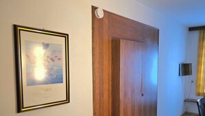 Um corredor com um quadro na parede, uma porta de madeira e uma pia branca.