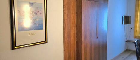 Um corredor com um quadro na parede, uma porta de madeira e uma pia branca.