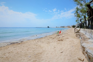 Na praia, areia branca, guarda-sóis, toalhas de praia 