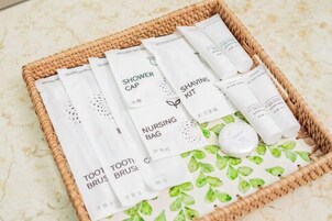Uma cesta de vime com diversos artigos de higiene pessoal, como touca de banho, kit de barbear, bolsa para amamentação e escovas de dentes.