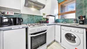 Cozinha compacta com fogão a gás, forno e máquina de lavar embutida.