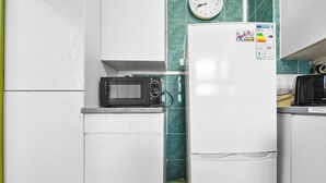 Cozinha com armários brancos, micro-ondas e geladeira.