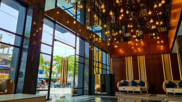 Um lobby moderno com grandes janelas de vidro, teto alto e luminárias pendentes.