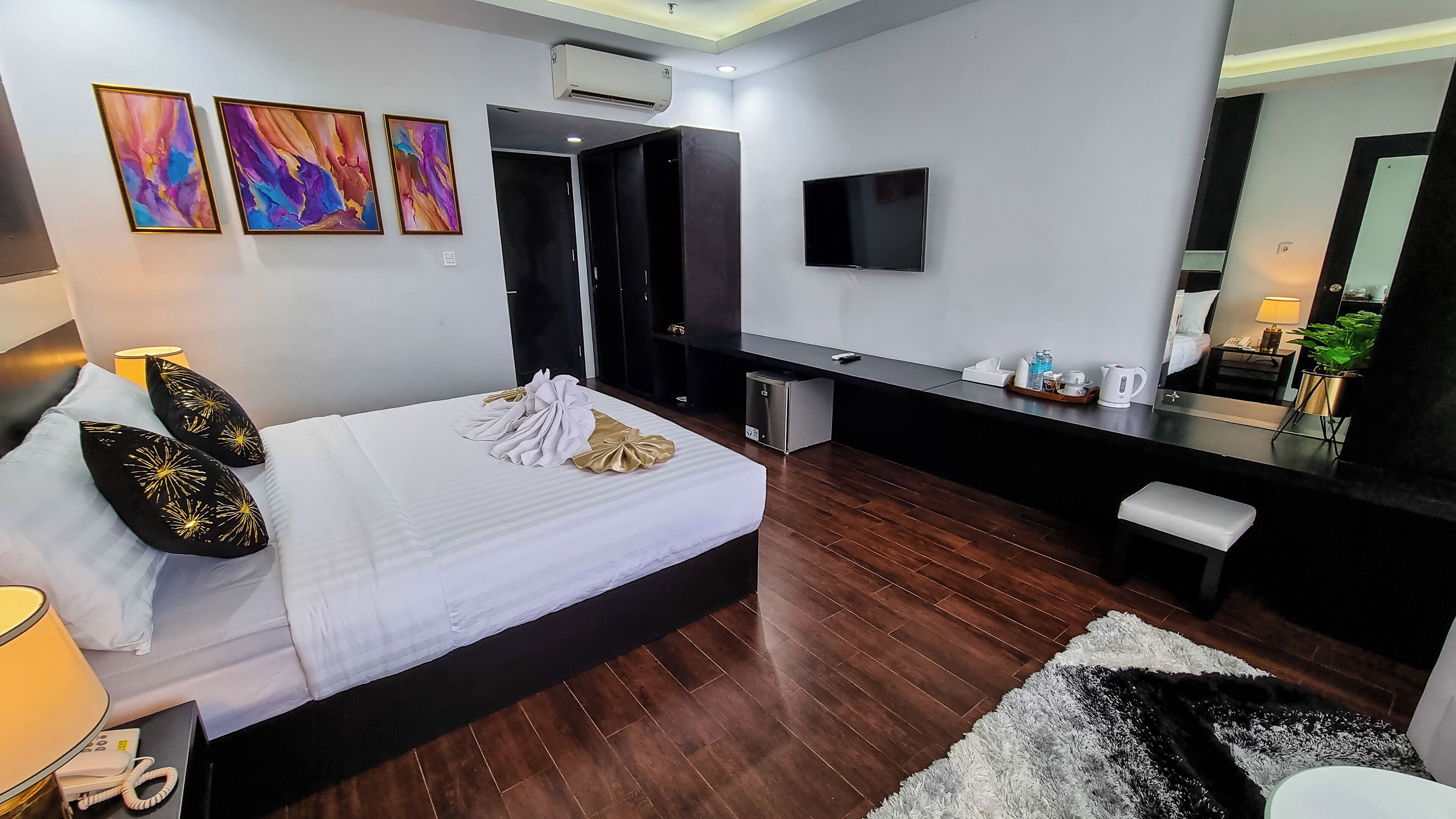 Quarto de hotel moderno com uma cama grande, televisão de tela plana, escrivaninha com cadeira e banheiro.