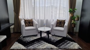 Uma sala de estar moderna com dois poltronas brancas, uma mesa redonda pequena e um tapete felpudo em preto e branco.