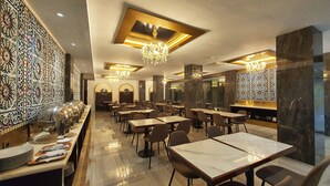Interior moderno de restaurante com chão de mármore, várias mesas de jantar e parede decorativa com padrões intrincados.