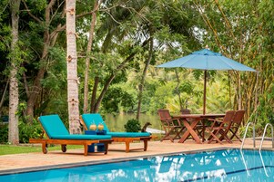 Uma área na piscina com espreguiçadeiras, uma mesa e um guarda-sol.