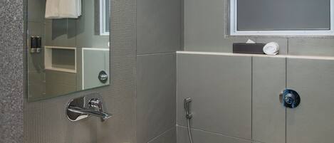 Uma casa de banho moderna com um espelho grande, lavatório suspenso, sanita e chuveiro.