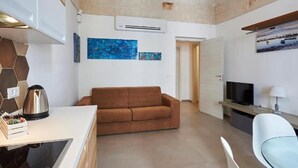 Um espaço de estar moderno com sofá, TV, cafeteira e obras de arte nas paredes.