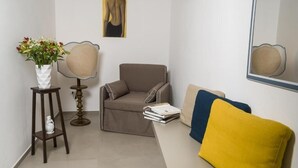 Quarto moderno com sofá marrom, almofada amarela, vaso branco com flores e uma obra de arte emoldurada na parede.