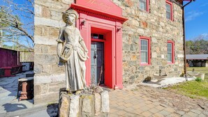Um edifício de pedra com uma porta vermelha e uma estátua na frente.