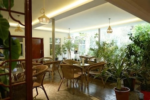 Quarto com mobiliário de vime, grandes janelas e luminárias pendentes.