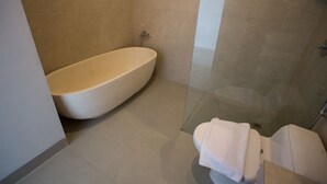 Um banheiro moderno com banheira livre, box de vidro e vaso sanitário com toalha.