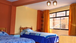 Quarto com duas camas, cabeceira de madeira, mesa de cabeceira e janela com cortinas.