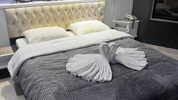 Quarto com cama grande, cabeceira estofada, roupa de cama branca e um mural na parede retratando um caminho nevado.