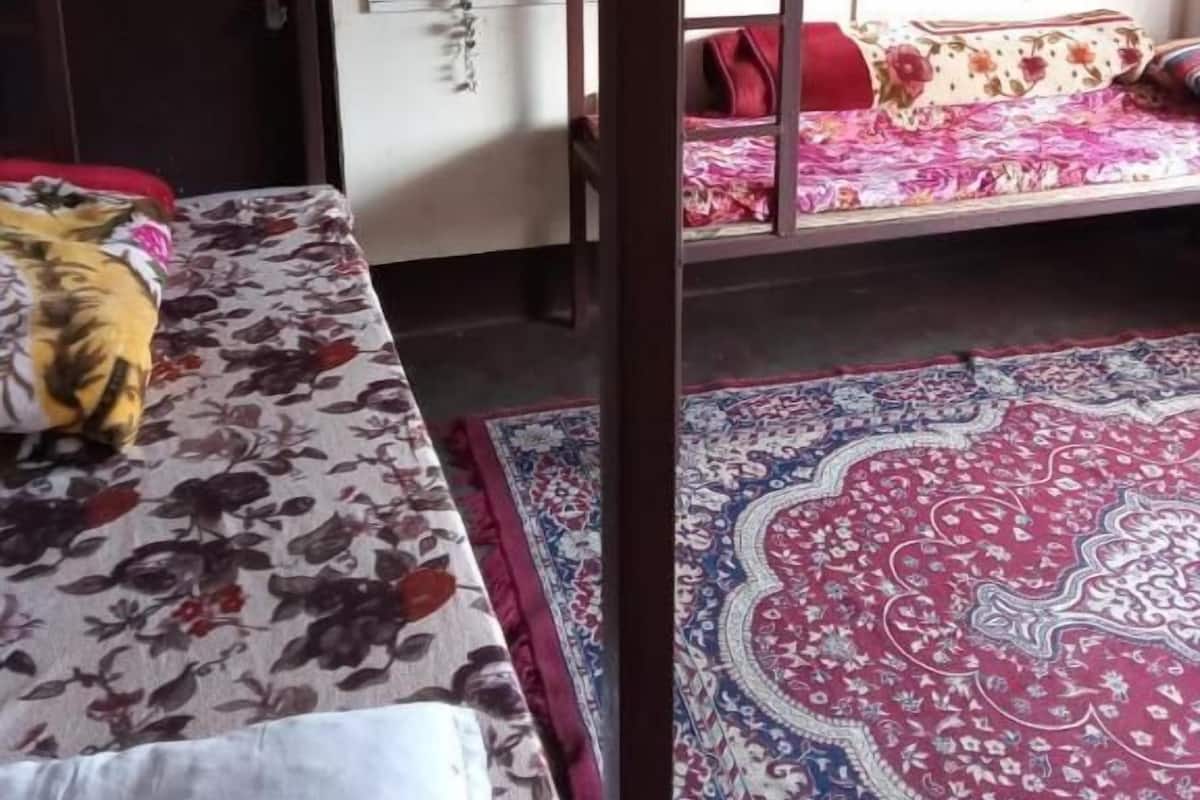 Quarto em dormitório com beliches, tapete estampado e uma pequena mesa.