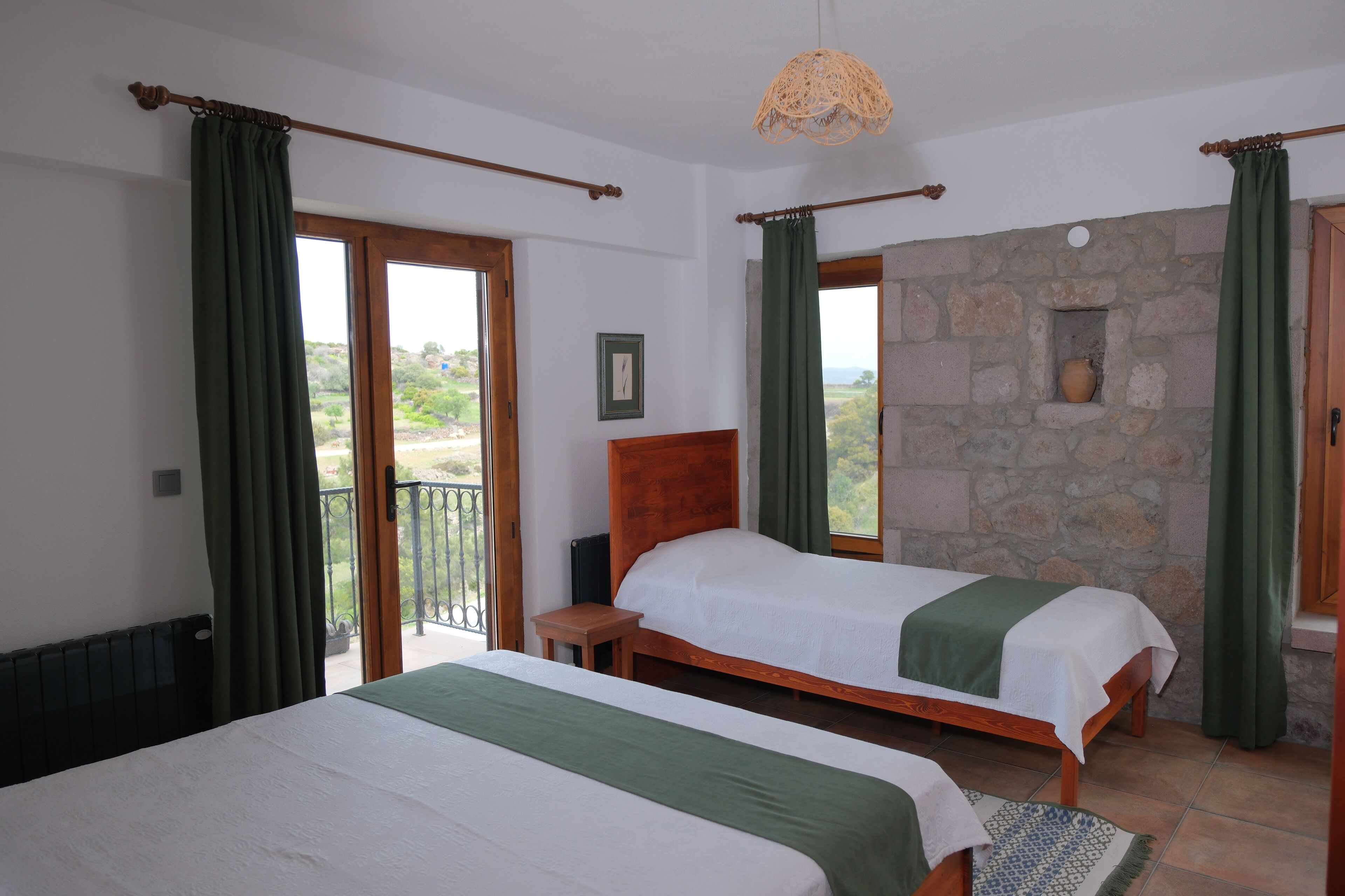 Quarto com duas camas, parede de pedra e varanda com vista.