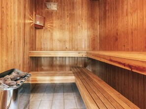 Uma sauna de madeira com bancos, assento e encosto.