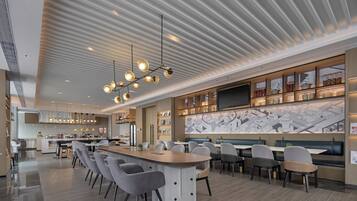 Um restaurante moderno com bar central, diversas áreas de estar e teto decorativo.