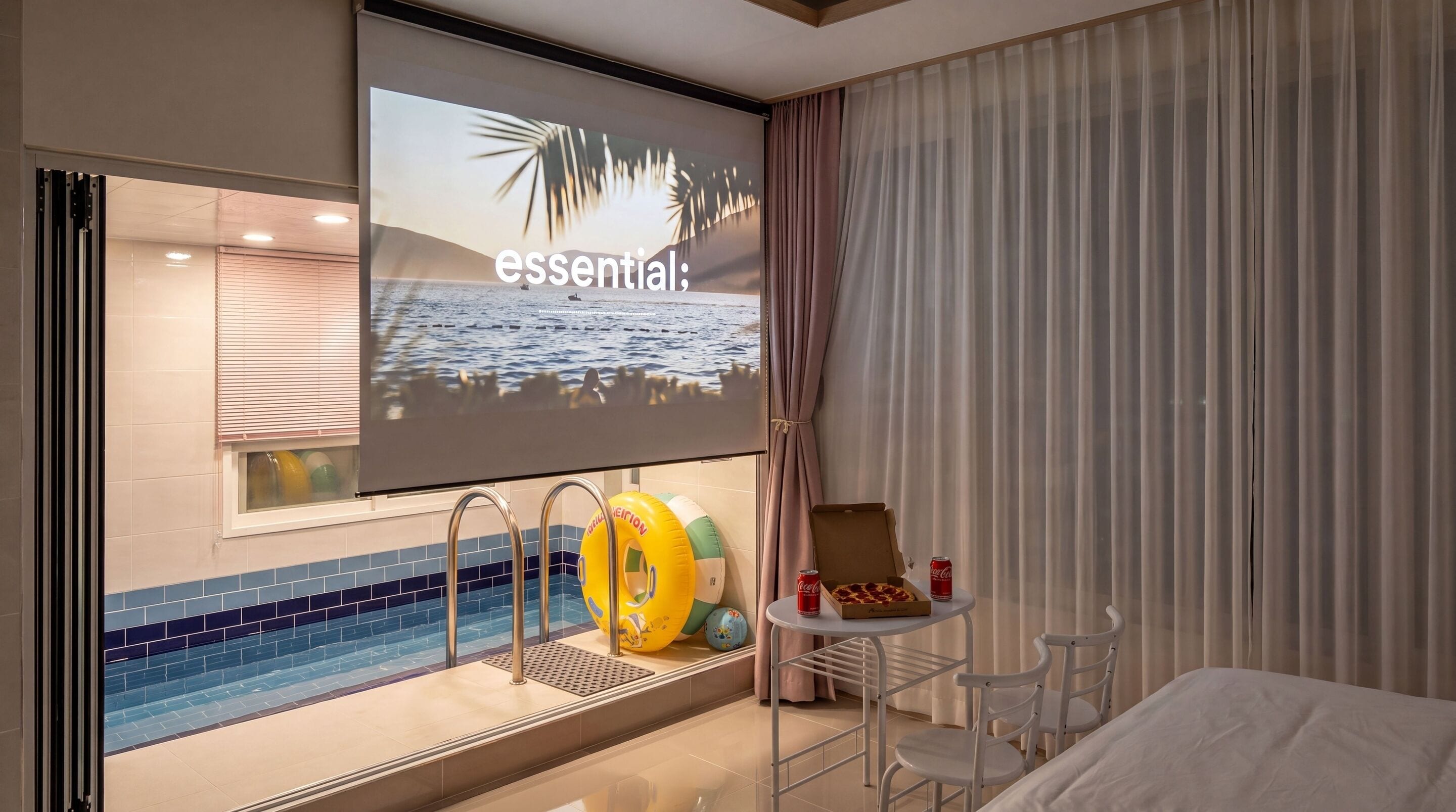Quarto de hotel com piscina, uma cama, uma tela de TV exibindo a palavra 'essential' e uma mesa com uma caixa de pizza e uma lata.