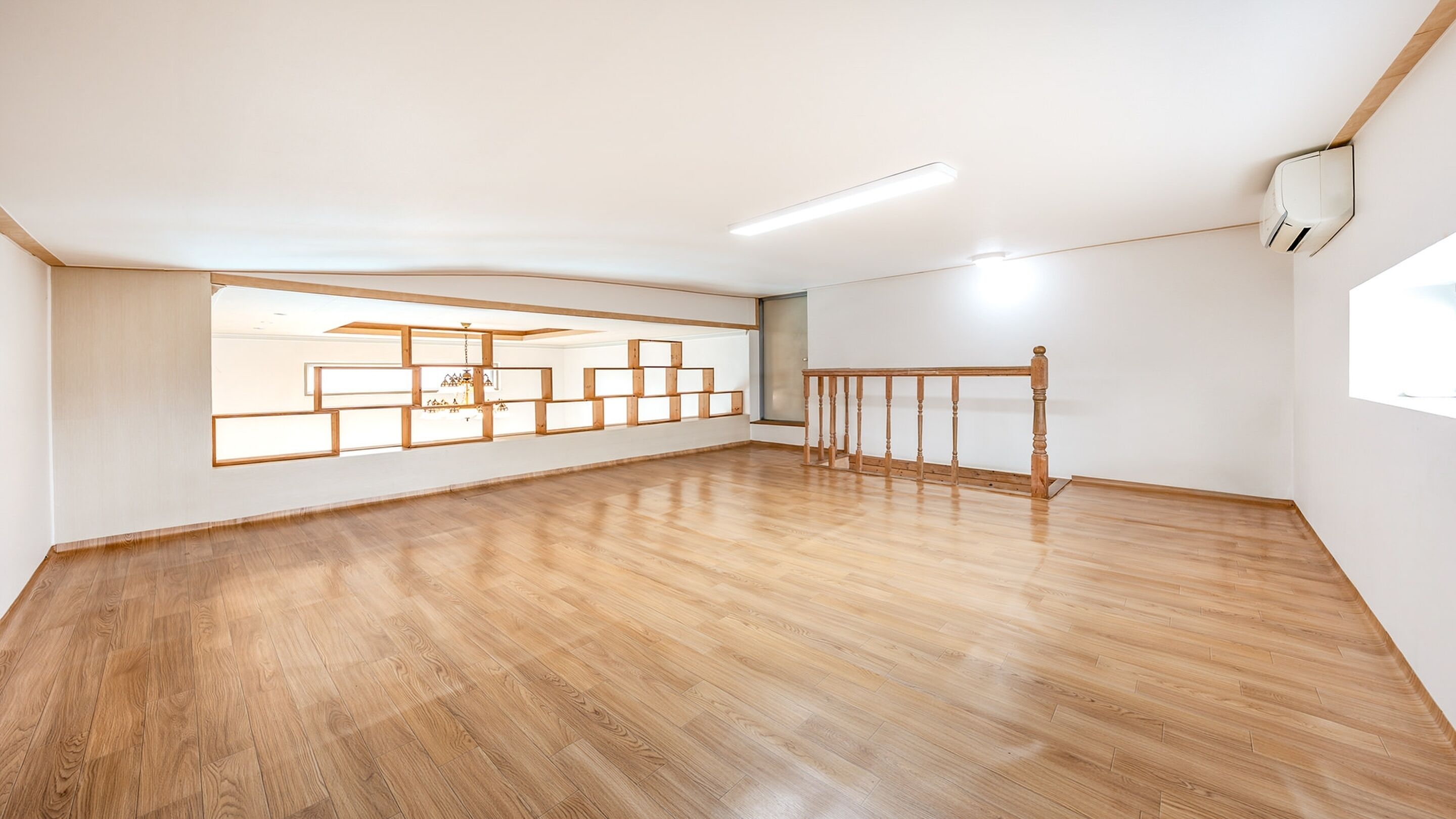 Um quarto amplo com piso e guarda-corpo de madeira, e grandes janelas.