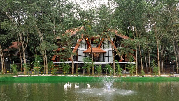 Um edifício com estilo arquitetônico tradicional, cercado por um lago com cisnes e uma fonte.