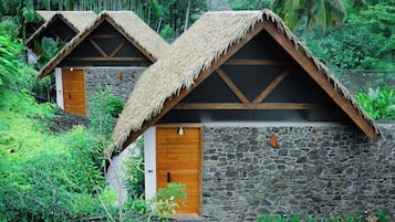 Uma cabana com telhados de palha, paredes de pedra e uma porta de madeira.