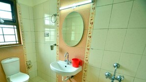 Casa de banho com sanita, lavatório, espelho e um balde vermelho.