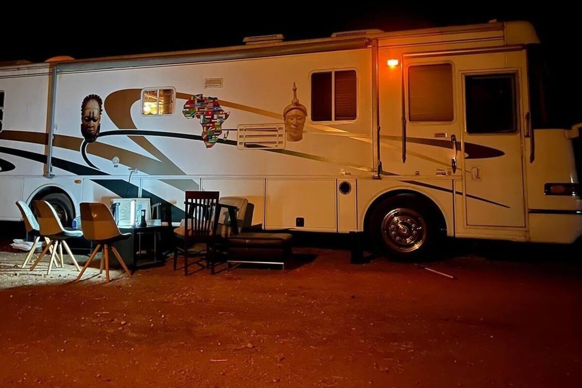 Uma motorhome grande com área de jantar, incluindo mesa e cadeiras, máquina de lavar e uma pequena cozinha.