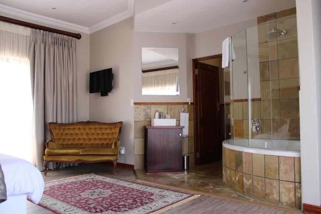 Uma casa de banho espaçosa com uma banheira grande, uma toucador com espelho e um sofá na área de estar adjacente.