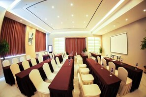 Sala de conferência com uma mesa grande, cadeiras, tela de projetor e quadro branco.