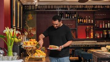Uma área de bar com um bartender servindo comida, prateleiras com garrafas e um ventilador de teto.