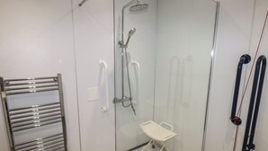 Um banheiro moderno com box de vidro, um banco branco e um porta-toalhas.